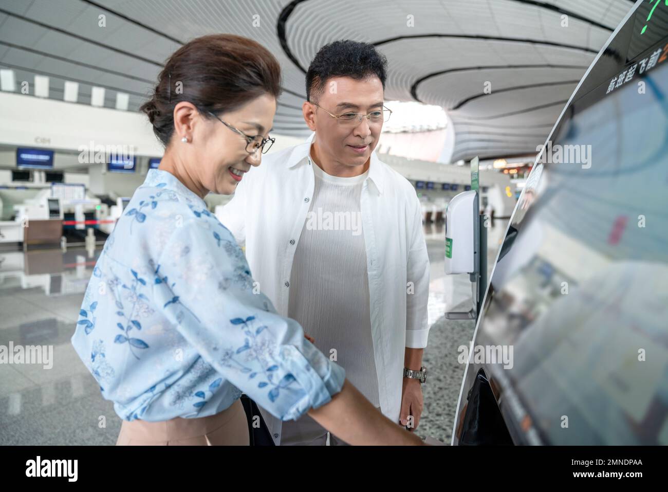 Happy elderly couple self-service ticket at the airport Stock Photo - Alamy