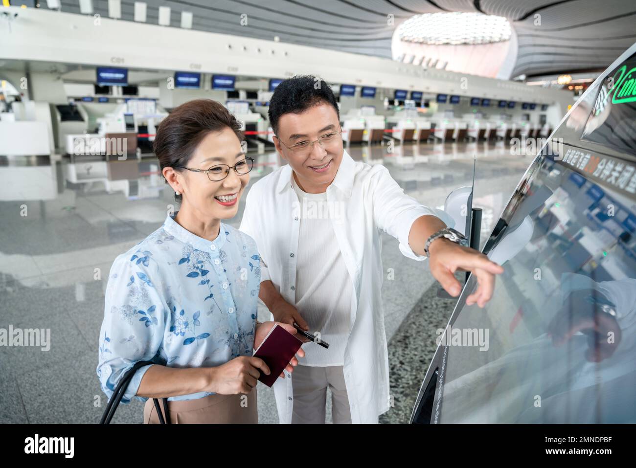 Happy elderly couple self-service ticket at the airport Stock Photo - Alamy