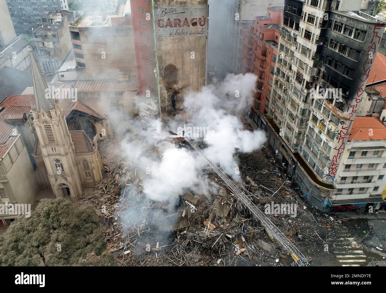 Firefighters work in the the rubble of a building that caught fire and ...