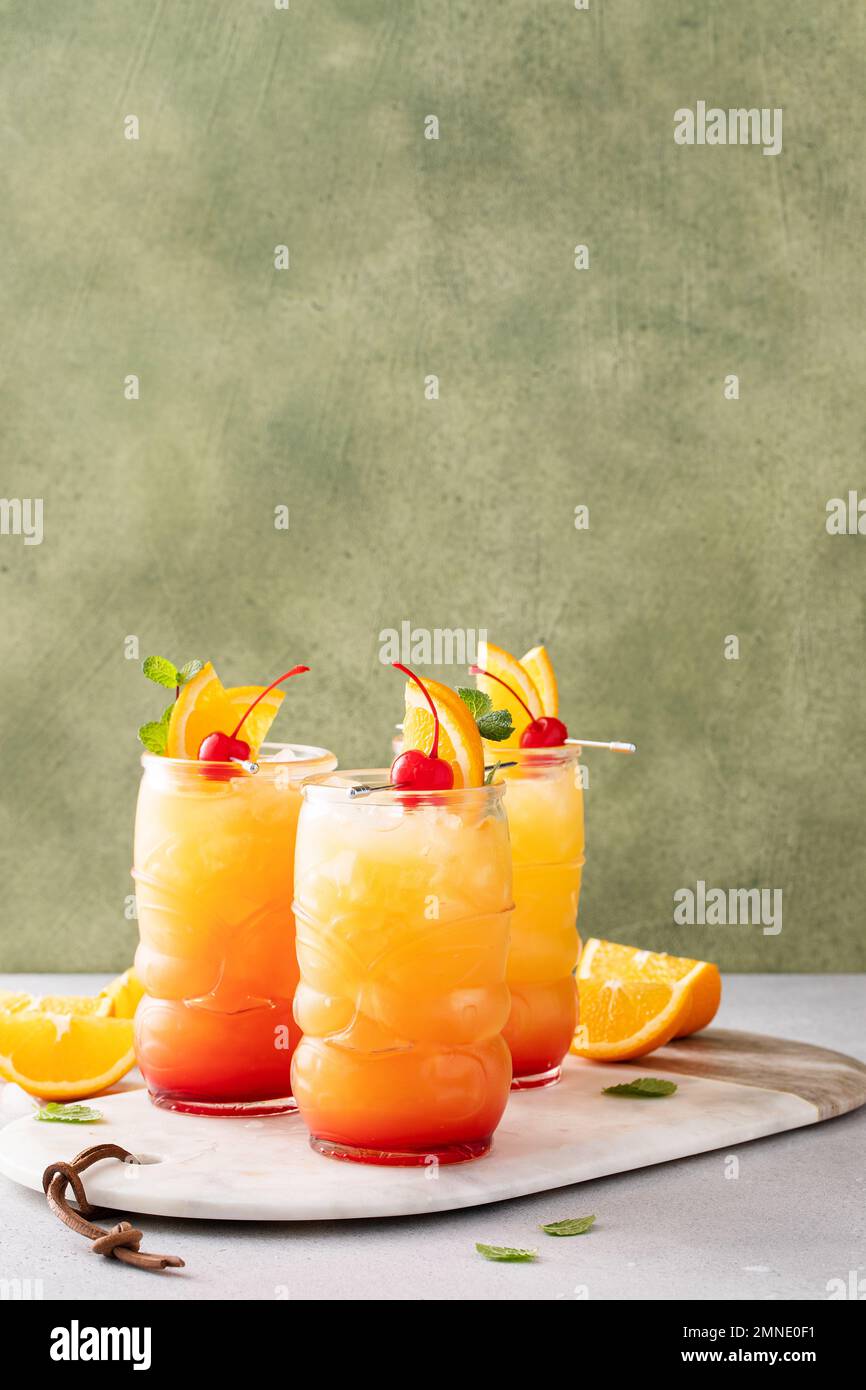 Rum punch in tiki glasses with orange slices and a cherry Stock Photo ...