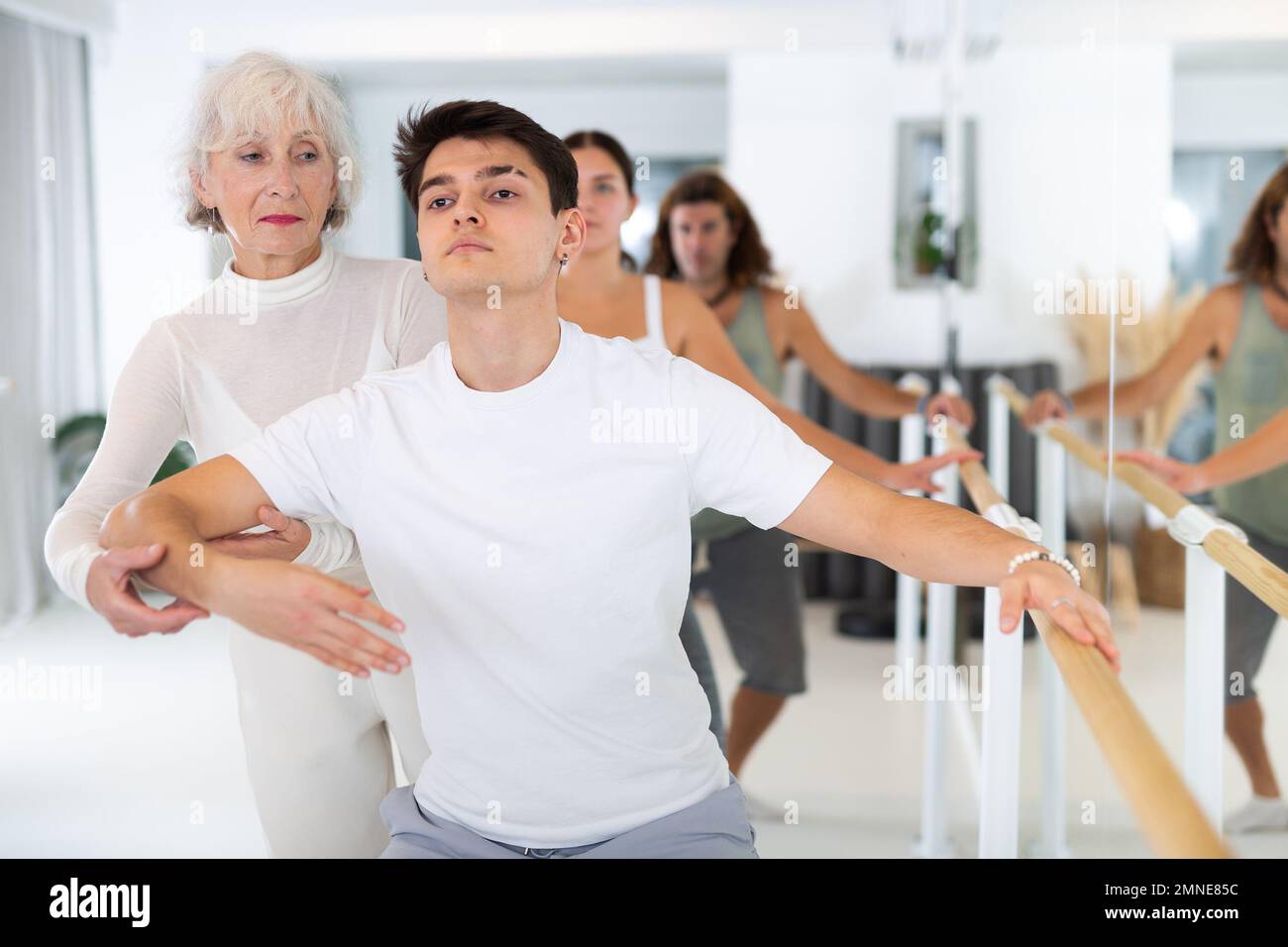 Female ballet teacher showing moves in front of group of different aged ...