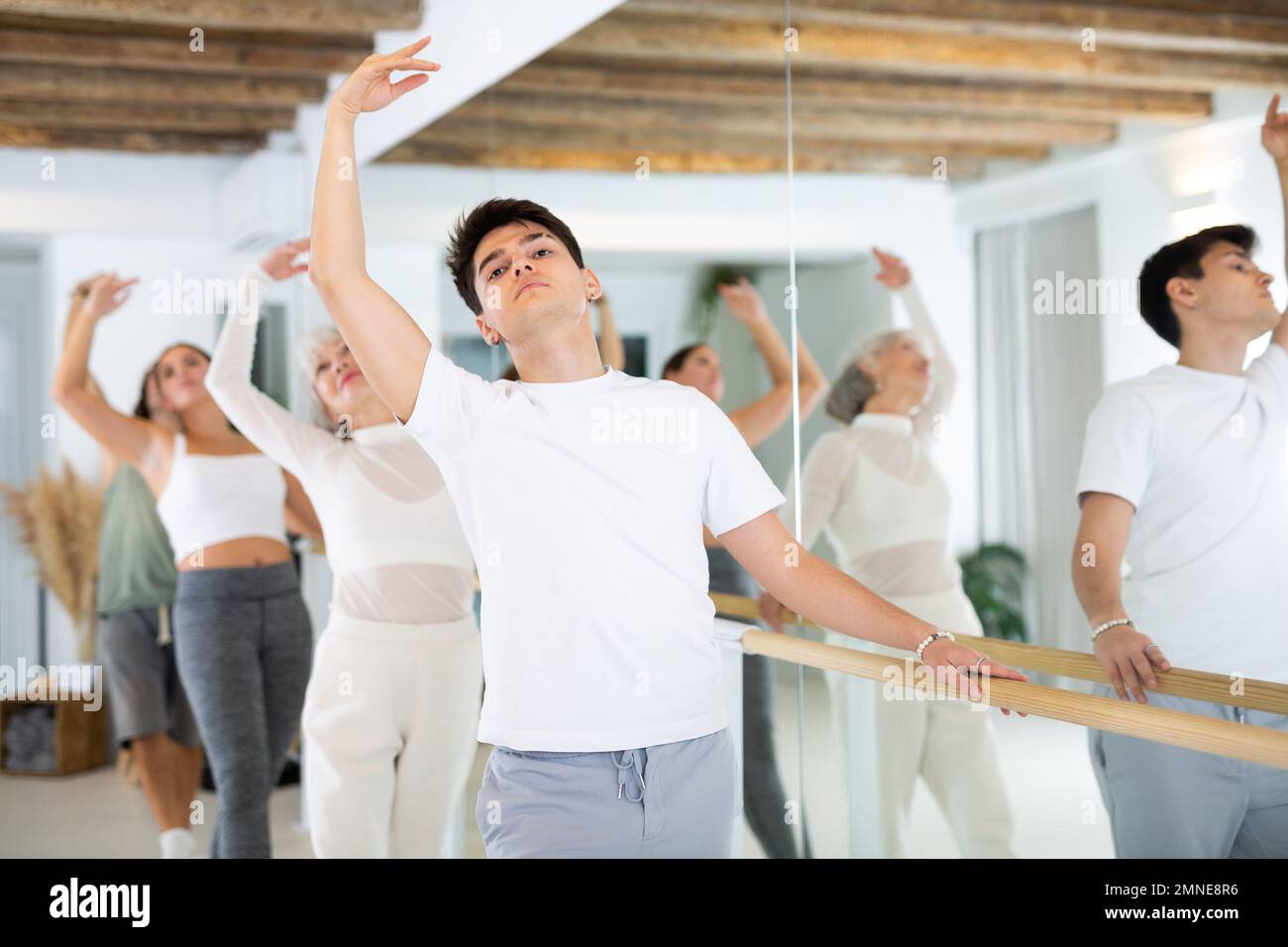Women and men training in ballet class with other dancers in studio ...