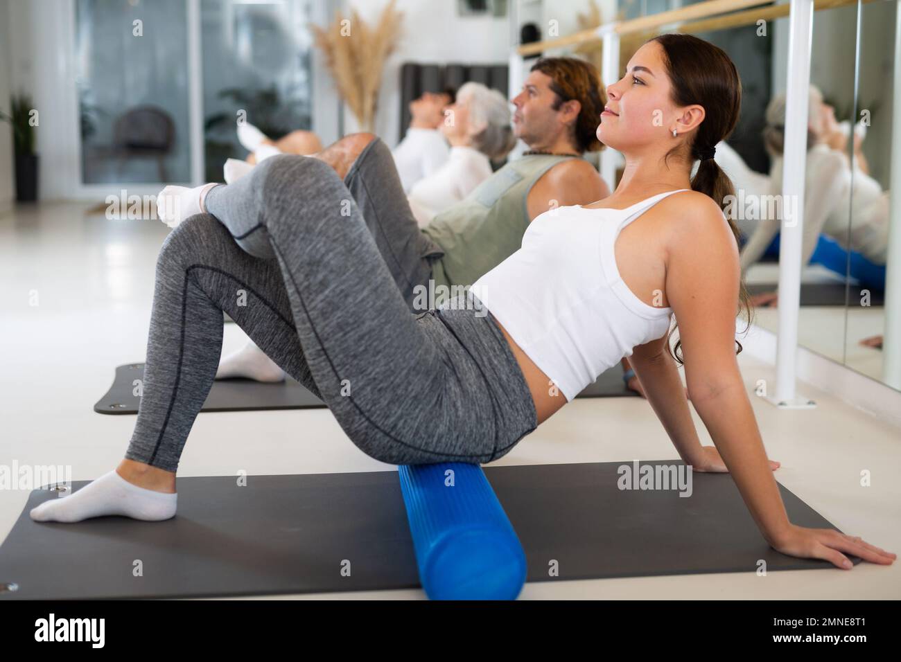 Young woman practicing pilates with roller in gym room Stock Photo - Alamy
