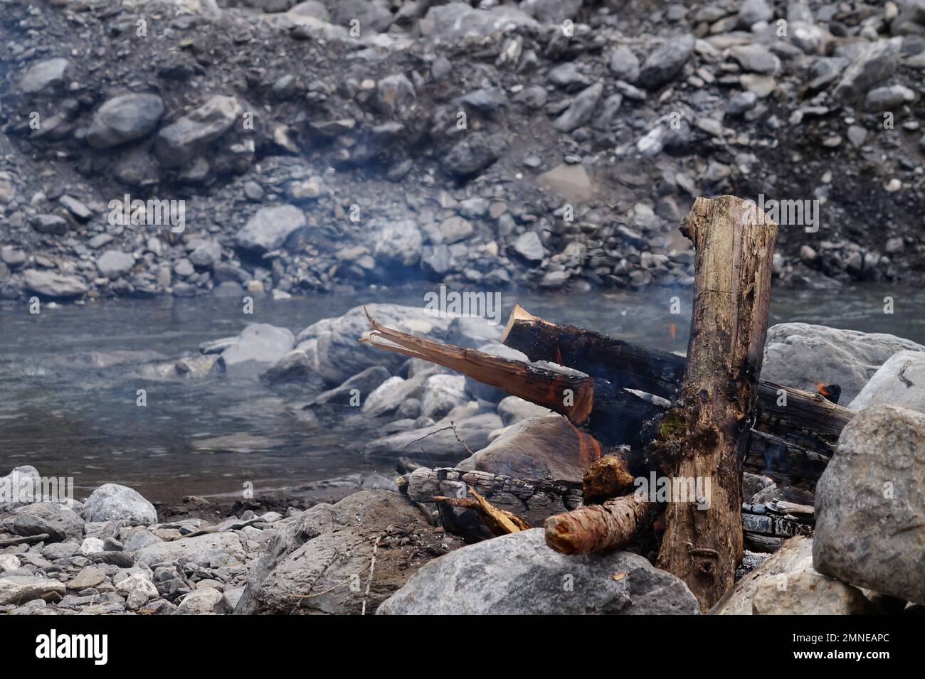 Close pictures of a campfire right next to a flowing river bed. Warm ...