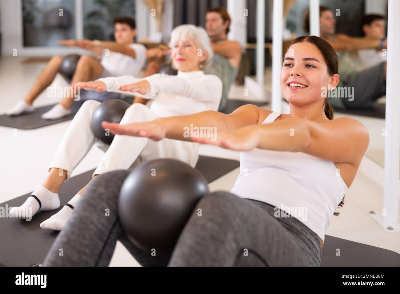 People different ages practicing pilates with ball at group class in ...