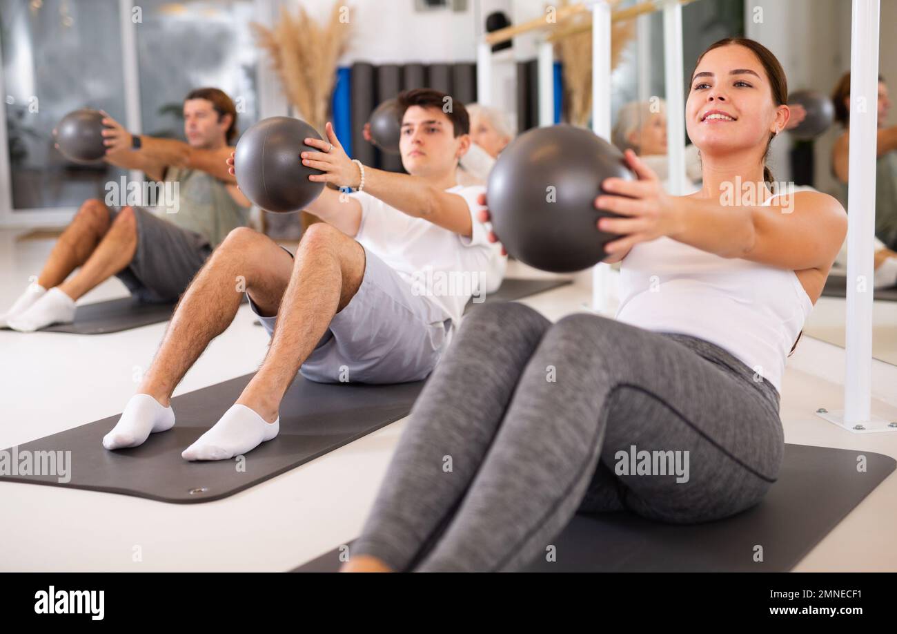 People different ages practicing pilates with ball at group class in ...