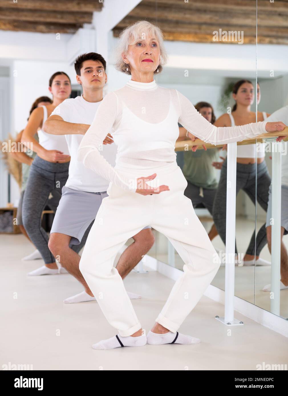 Women and men training in ballet class with other dancers in studio ...