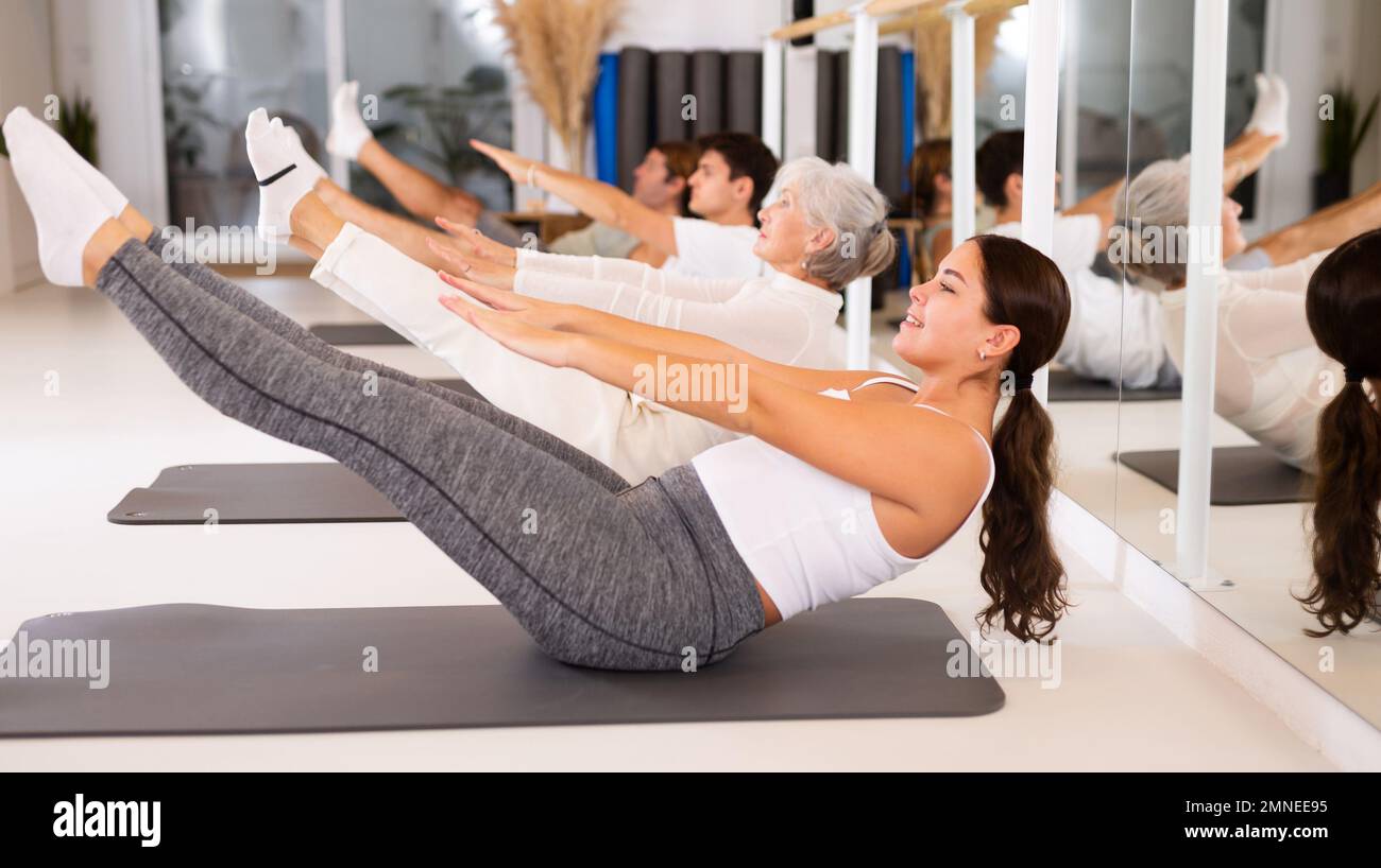 People different ages performing set of pilates exercises in fitness ...