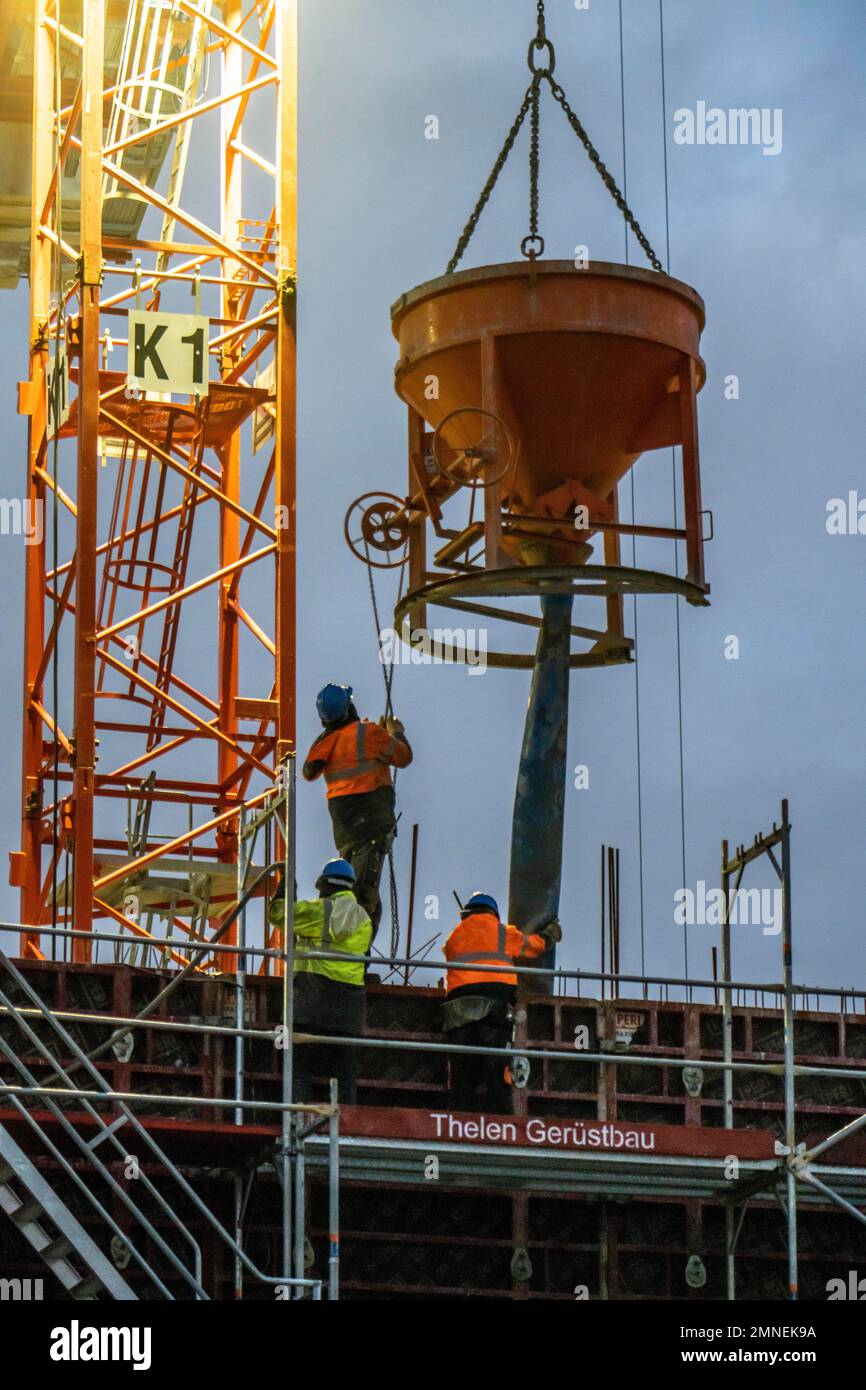 Concrete work, at dusk, on a large construction site building a ...