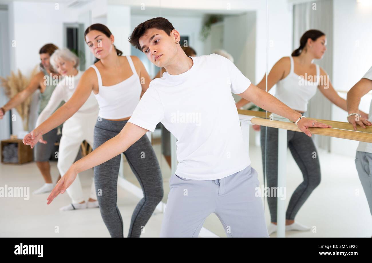 Women and men training in ballet class with other dancers in studio ...