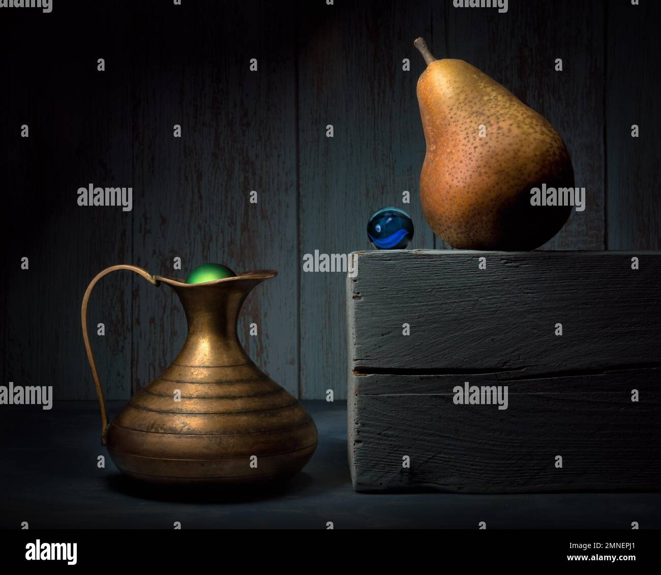 Still life with brass vase, pear and glass ball, studio shot, dark ...