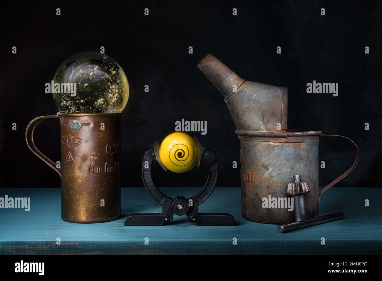 Still life with old oil can, glass ball, wooden ball in clamp and drill ...