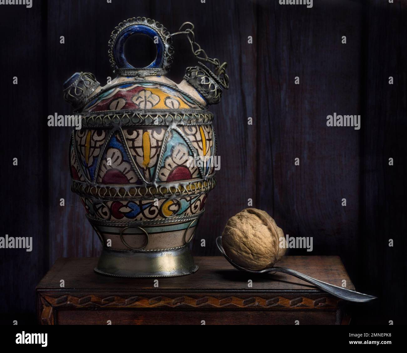 Still life with oriental vessel and walnut on spoon, studio shot, dark ...