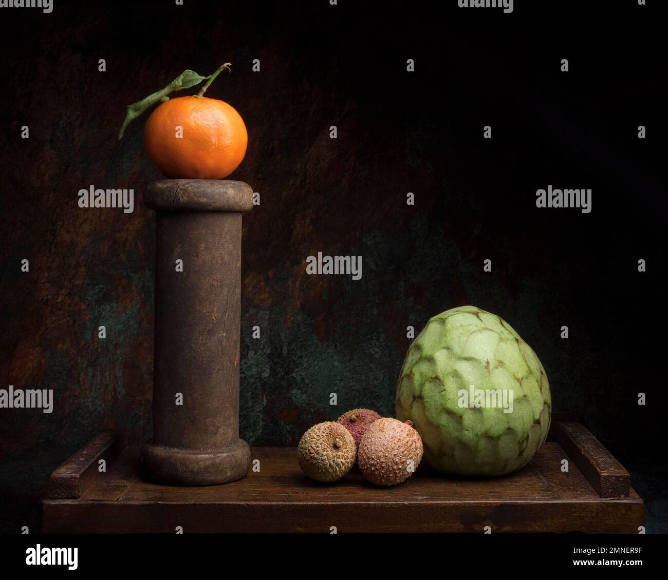 Still life with mandarin on wooden spool, lychees and cherimoya fruit ...