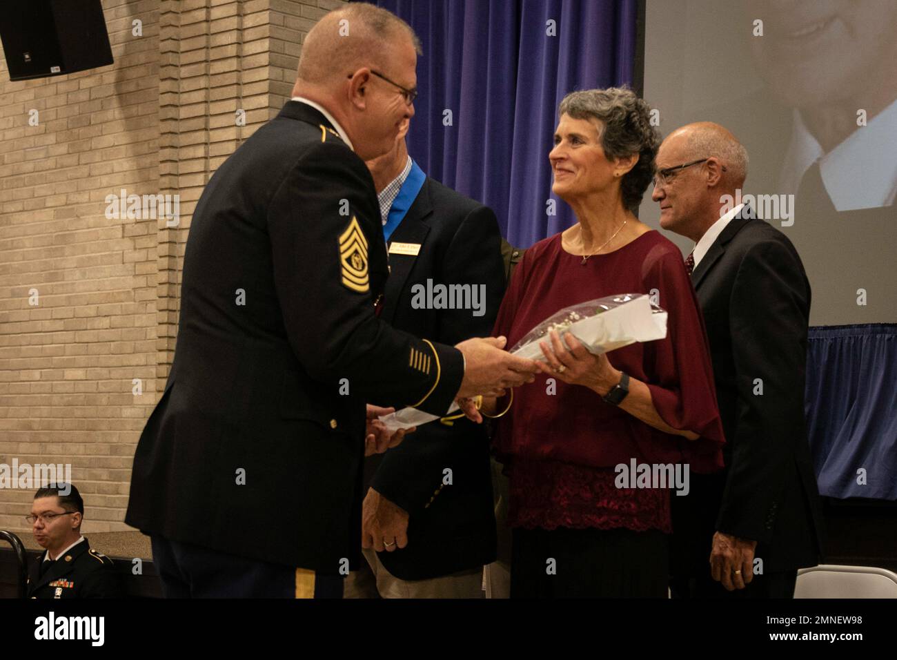 Minnesota’s Army Command Sgt. Maj. George Jensen presents a flower to ...