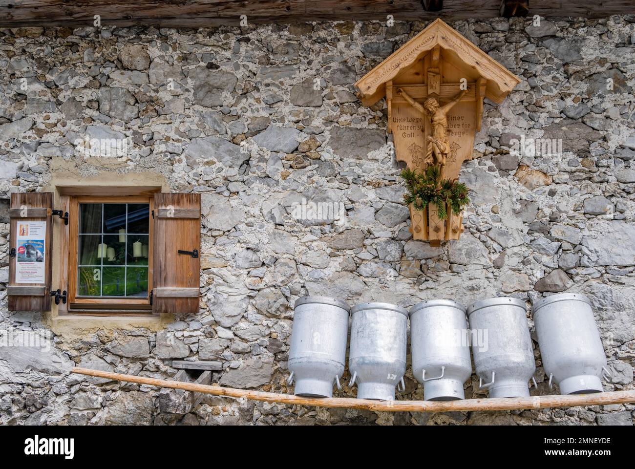 Milk cans lined up on a wooden bench, window and shrine with Jesus on ...