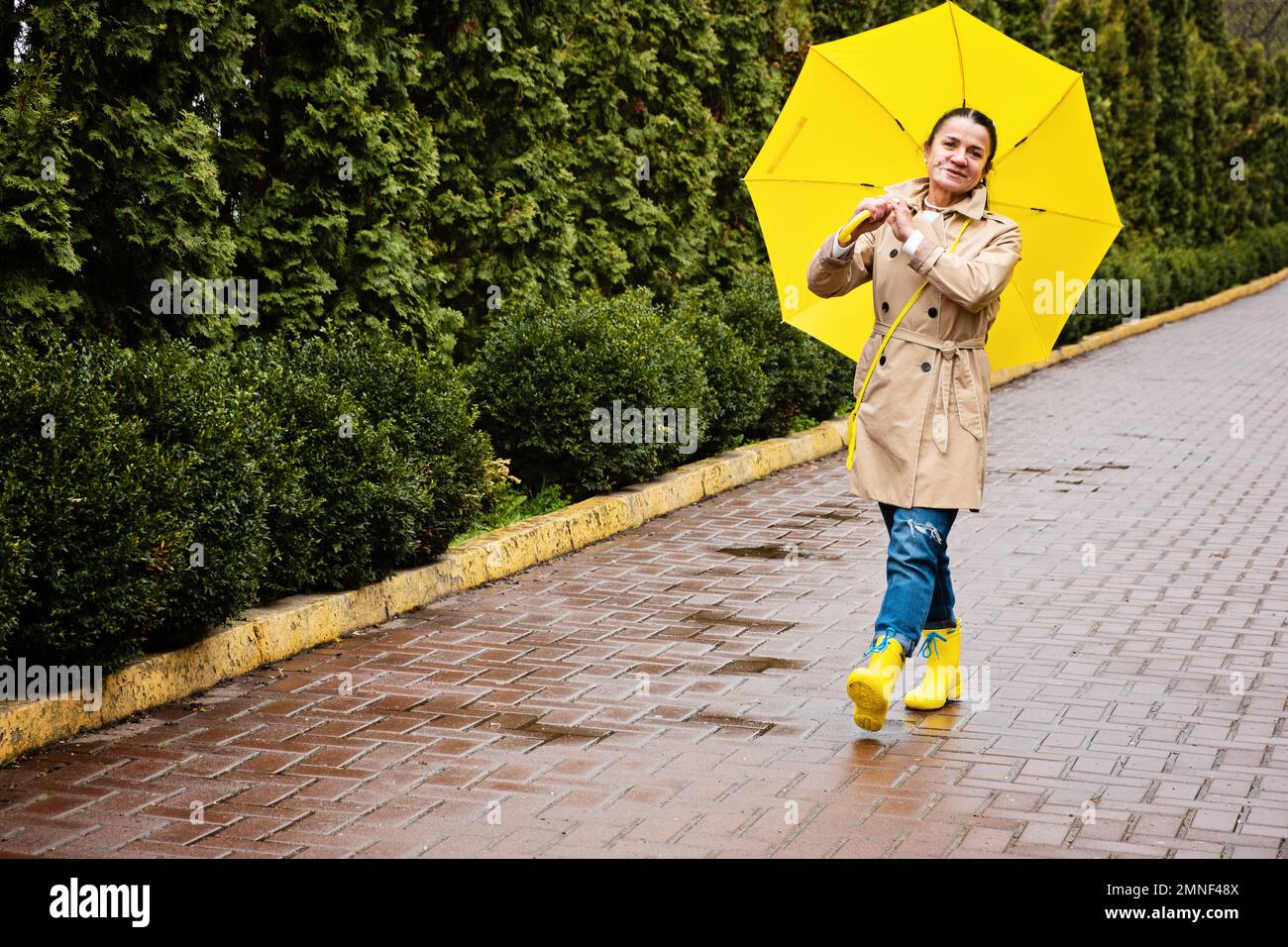 Happy Senior Woman In Yellow Rain Coat With Yellow Umbrella Encouraging