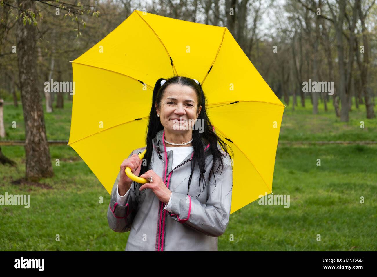 Happy Senior Woman In Yellow Rain Coat With Yellow Umbrella Encouraging