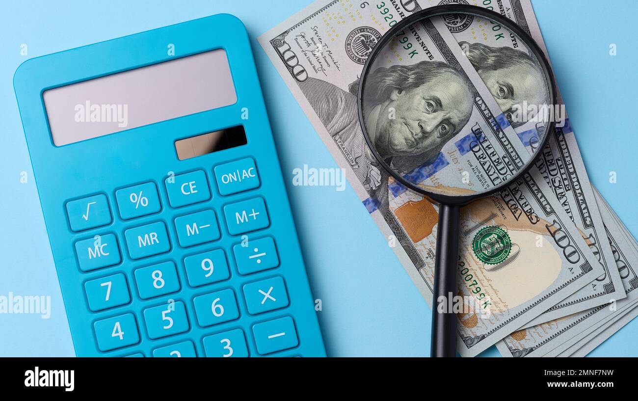 Blue calculator and a stack of one hundred dollar American bills on a ...