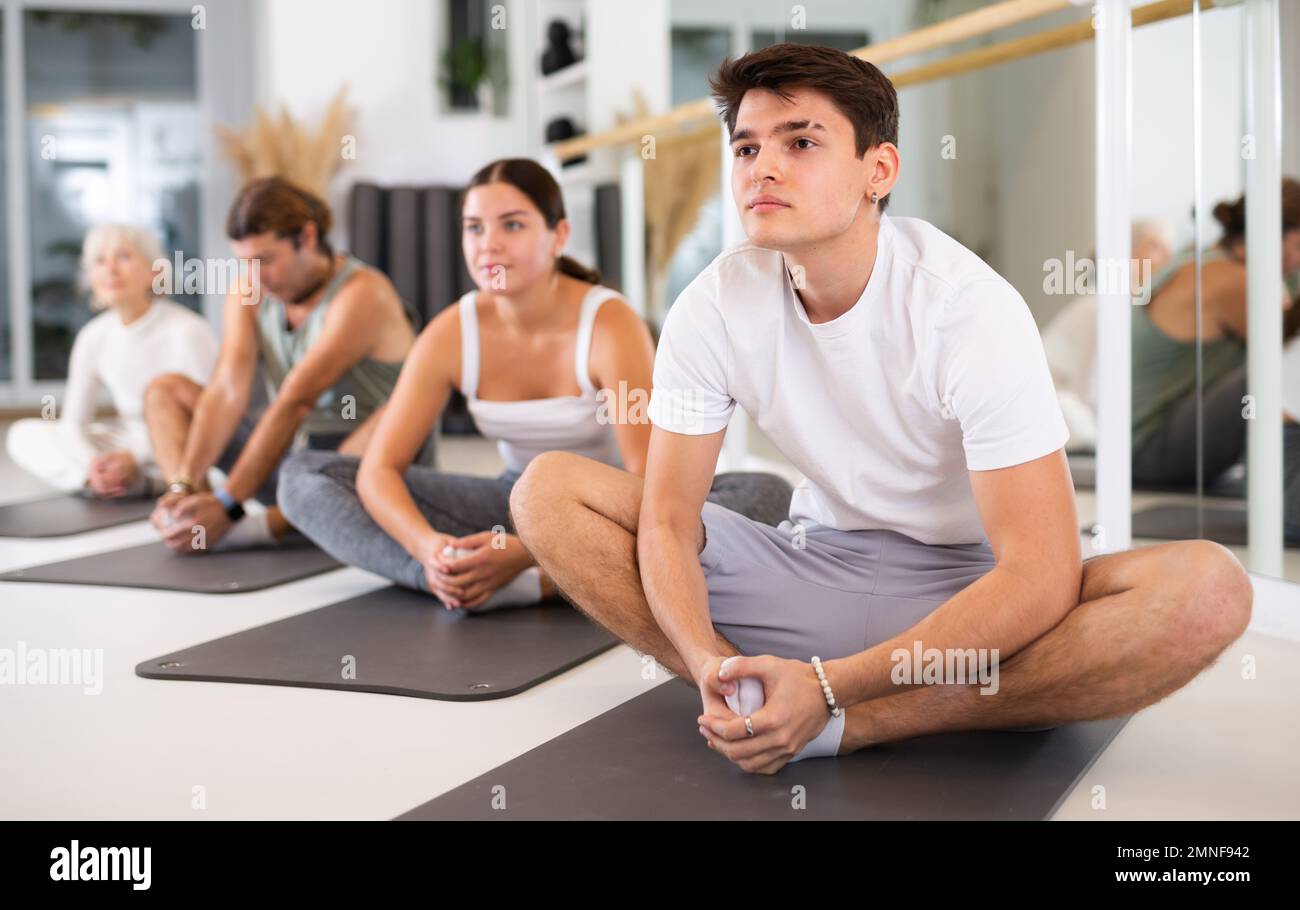 Positive athletic male performing set of exercises on a pilates mat ...
