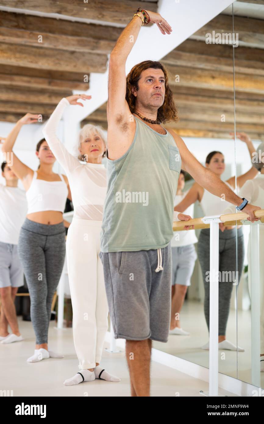 Women and men training in ballet class with other dancers in studio ...