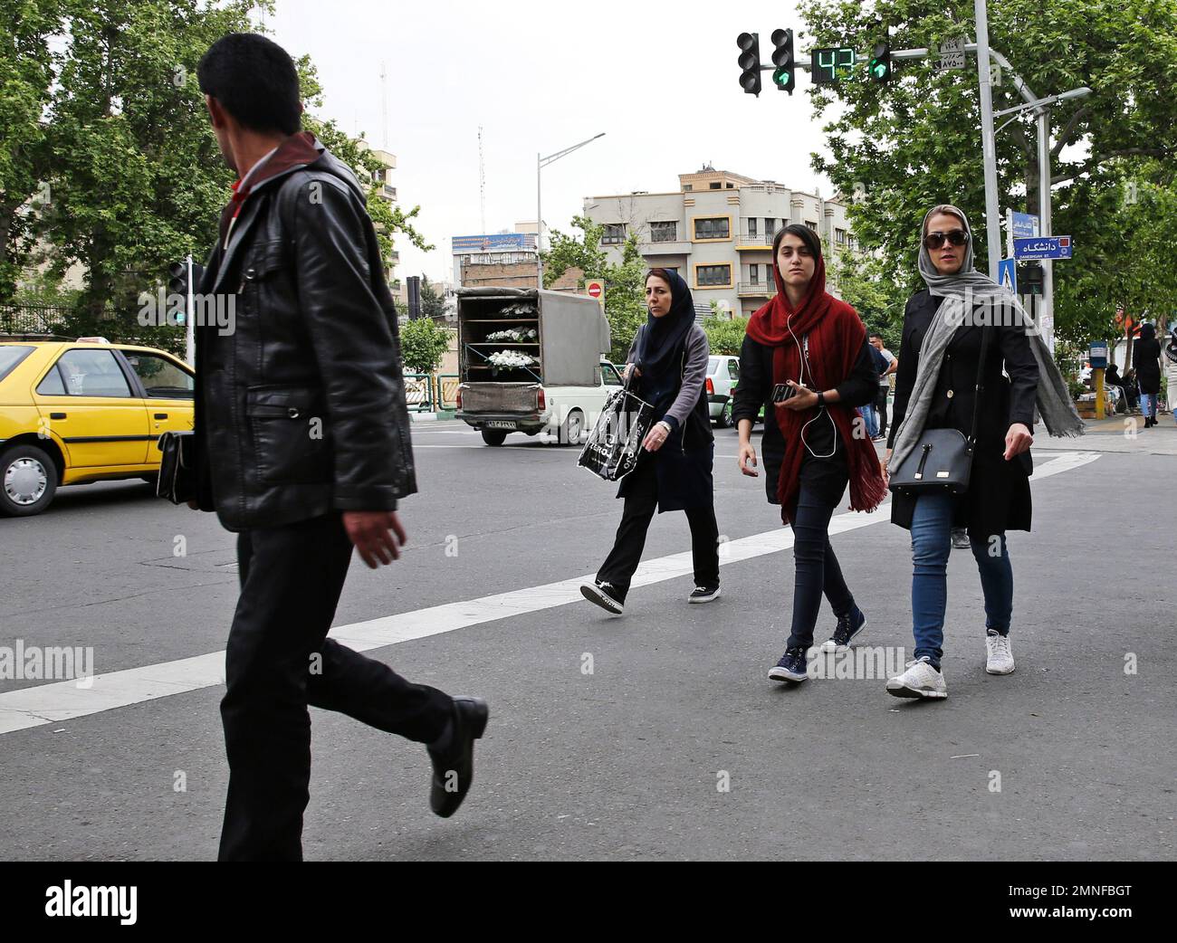 In this Sunday, April 22, 2018, photo, pedestrians cross a street in ...