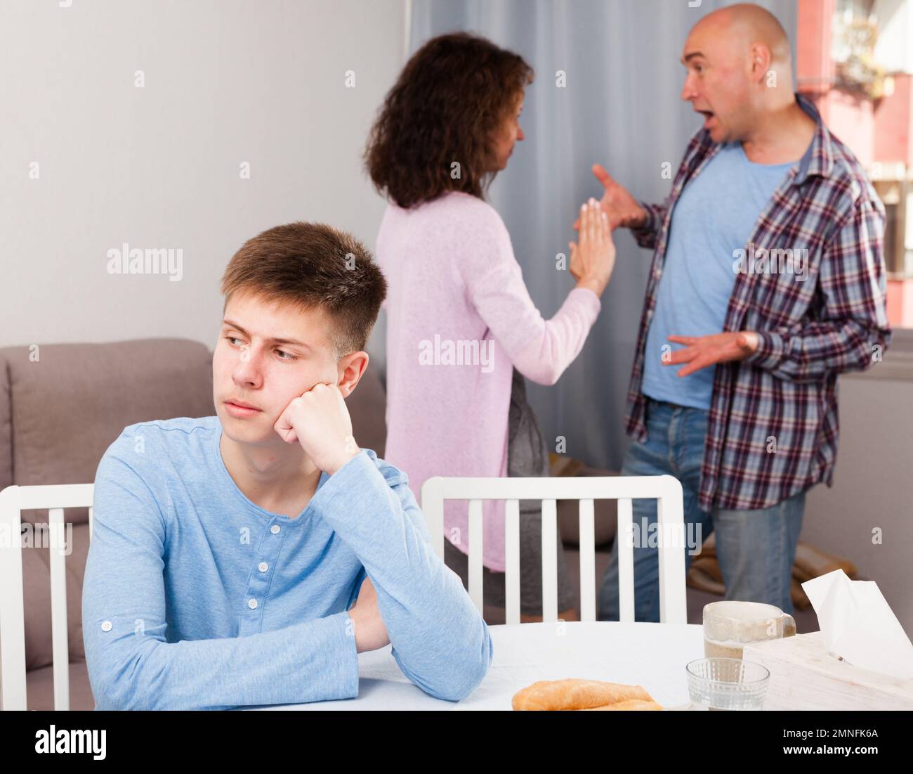 Unhappy teen boy with quarreling parents Stock Photo - Alamy