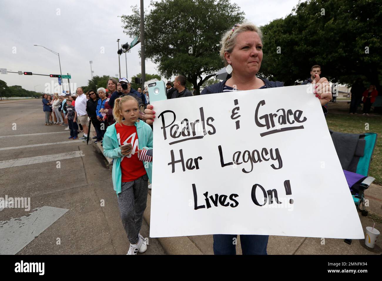 Kelly Yates holds up a sign as she waits on the route for the motorcade ...
