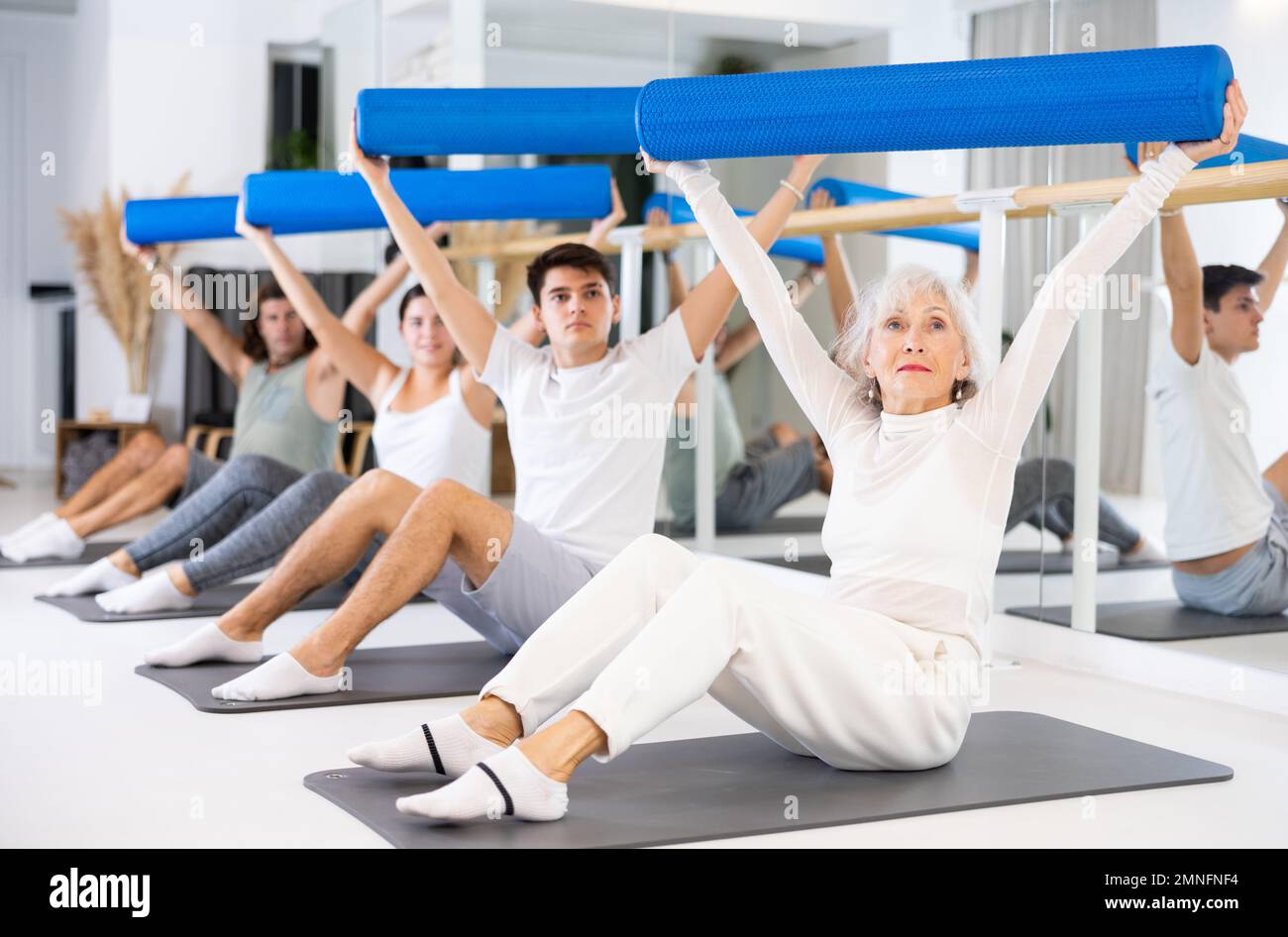 Group of people of different ages doing Pilates using rolled mats Stock ...