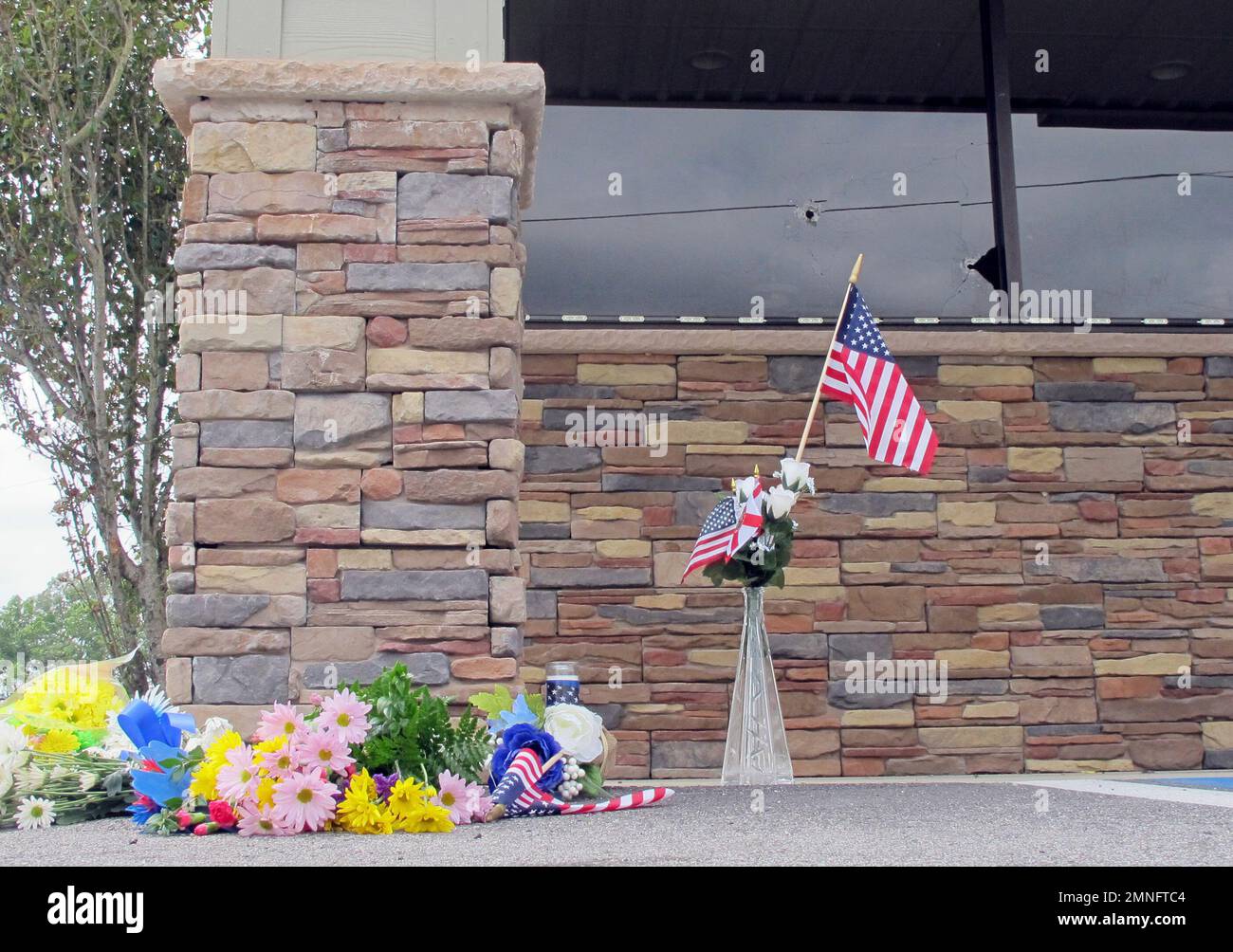 A memorial of with a flag and flowers sits in front of a restaurant ...