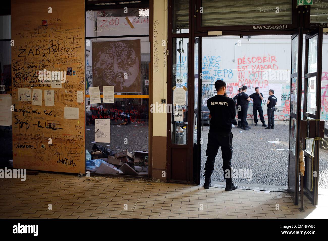 Security guards stand next to walls covered with graffiti by students ...