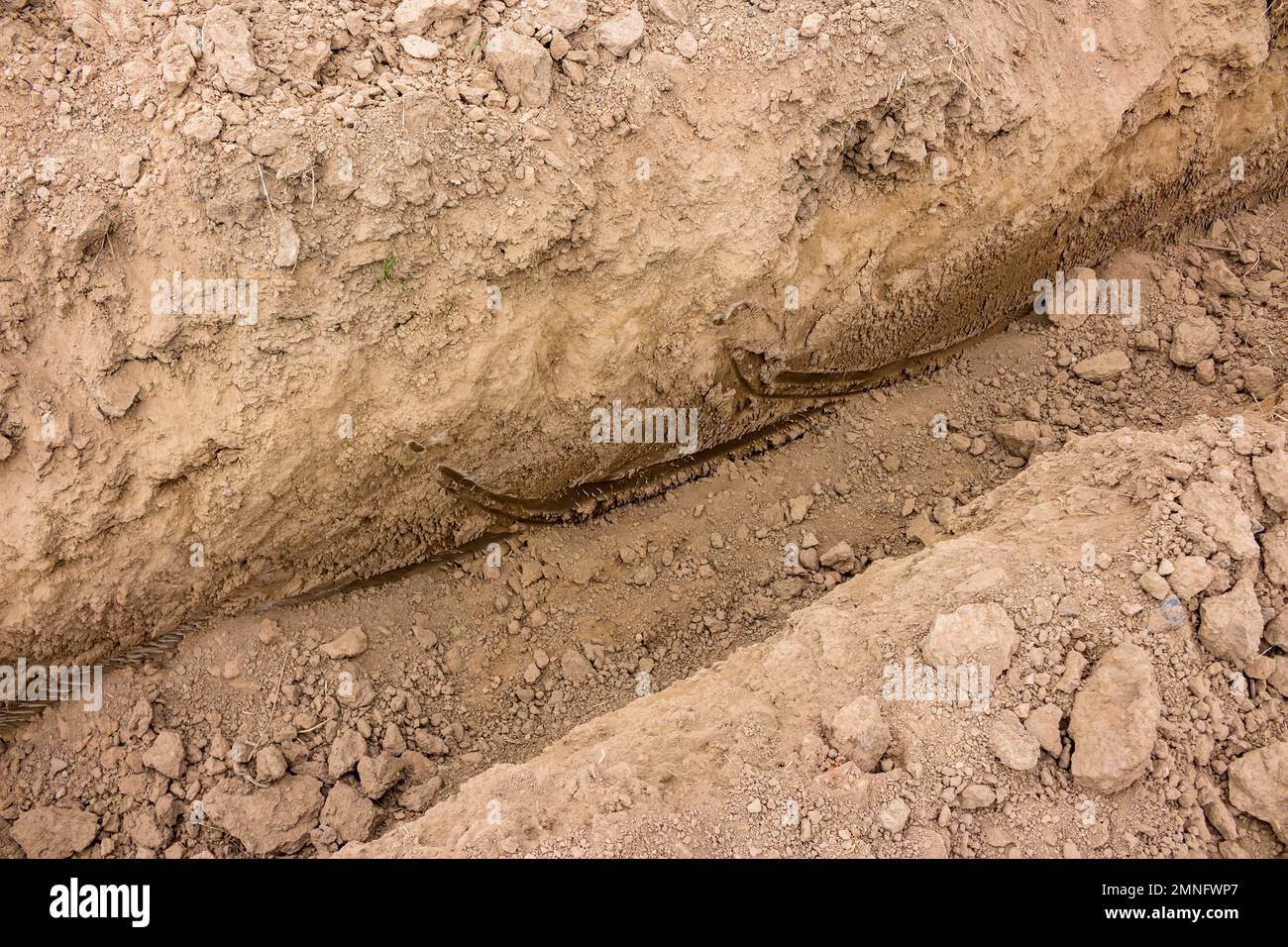 Trench in the ground dug by an excavator Stock Photo - Alamy