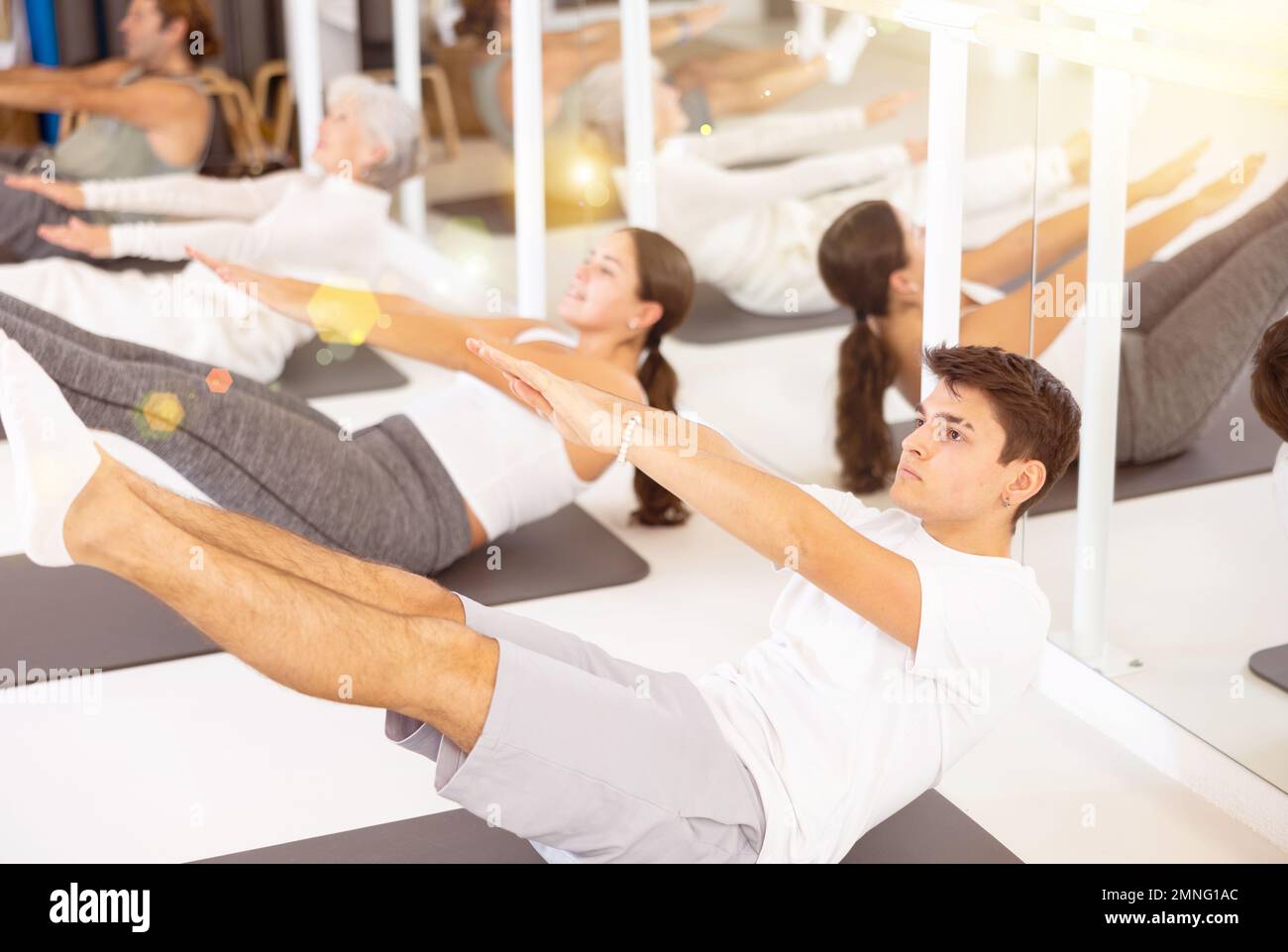 Positive athletic male performing set of exercises on a pilates mat ...