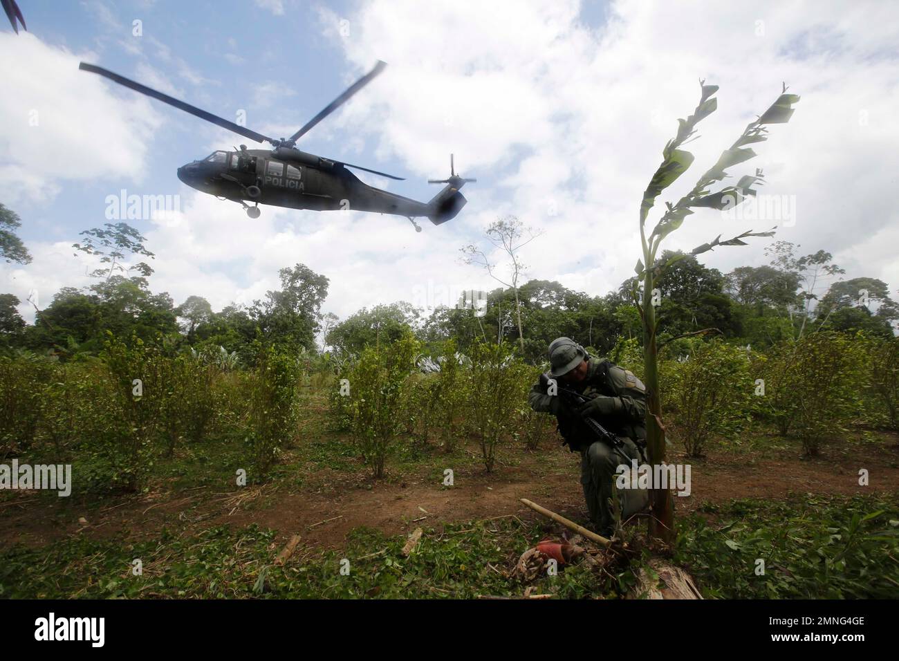 A counter narcotics police officer takes cover as a helicopter lands on ...