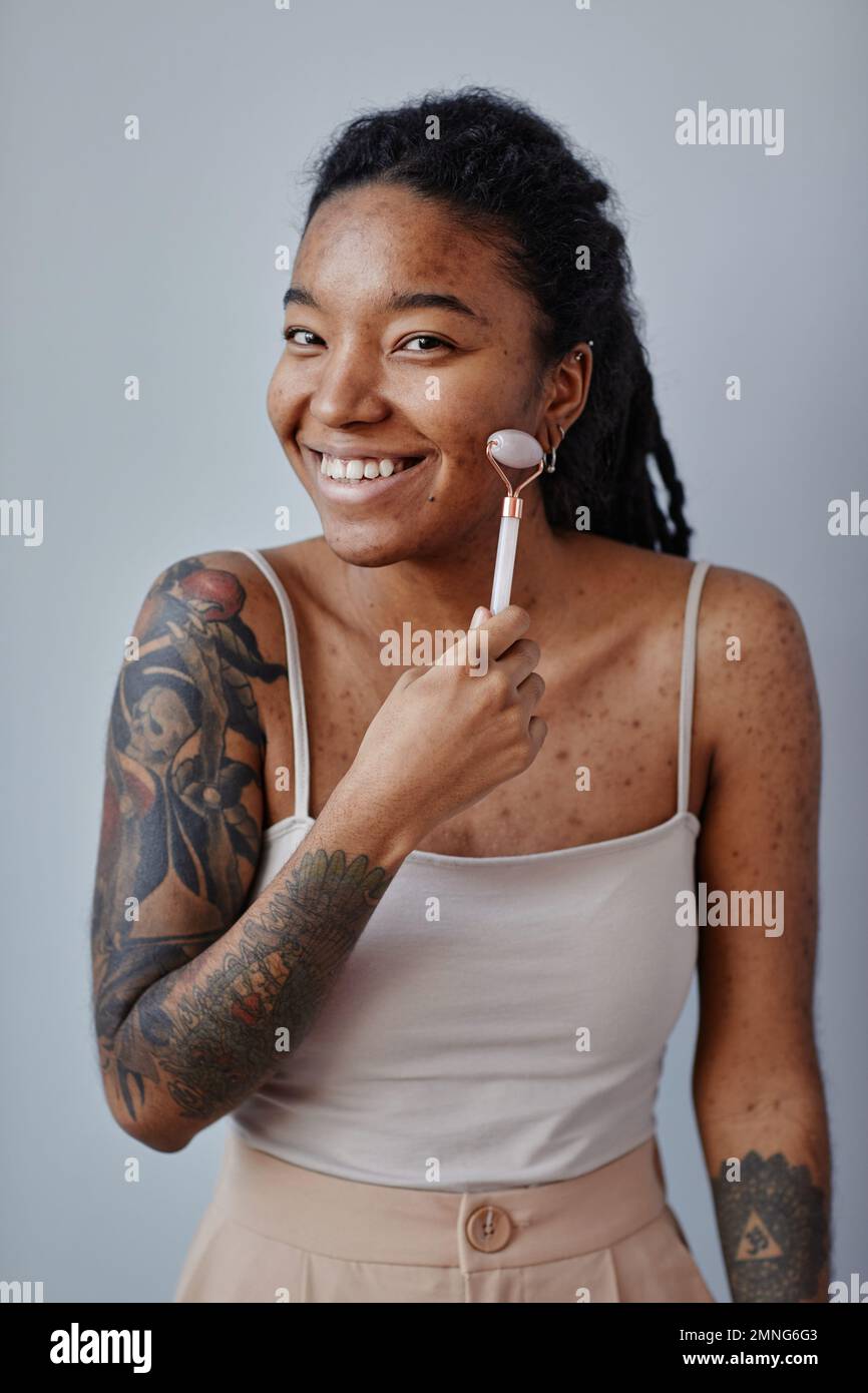 Vertical portrait of young black woman with acne scars and tattoos ...