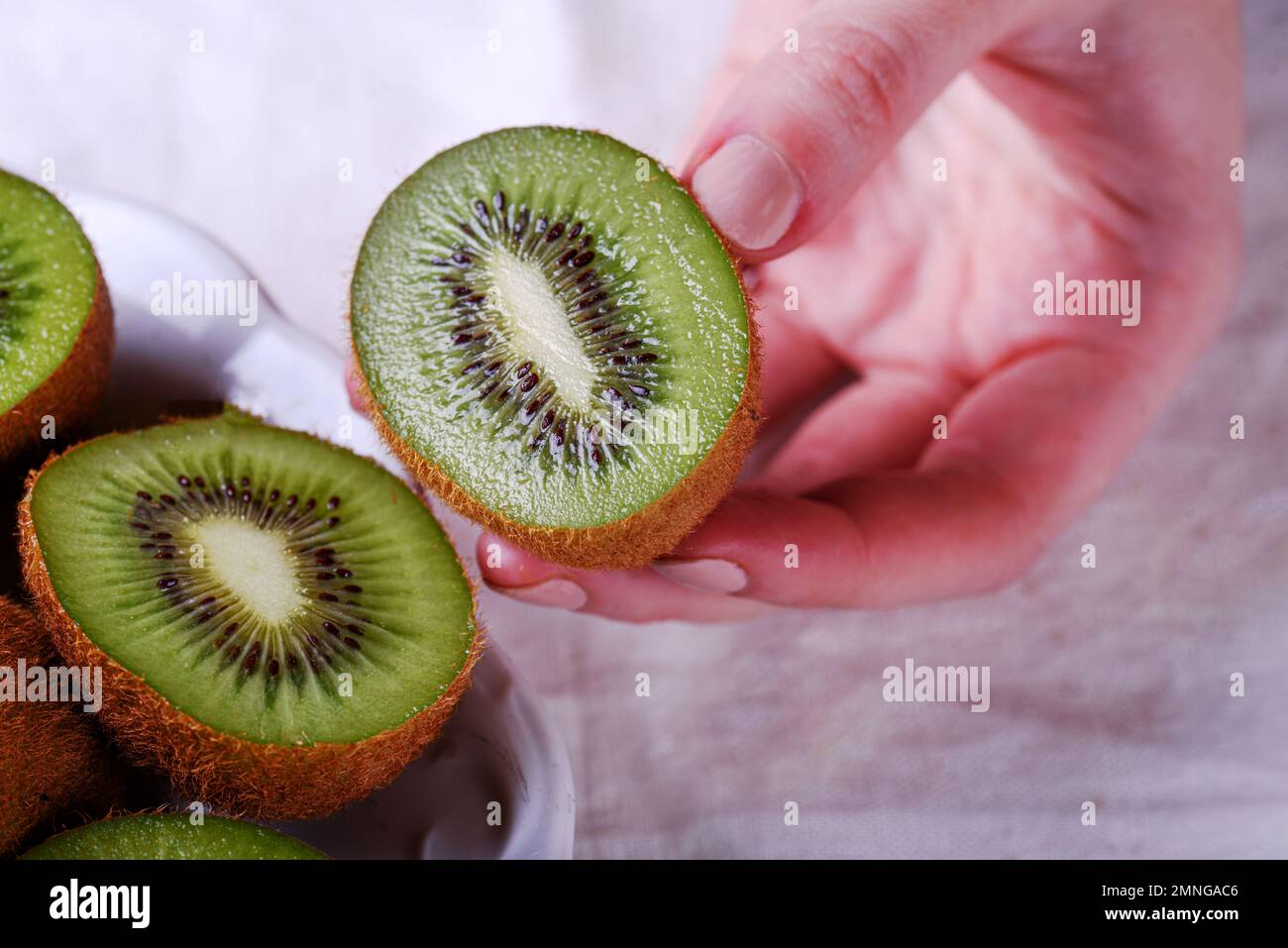Kiwi. Chopped kiwi on chopping board. Half of a kiwi in a woman's hand ...