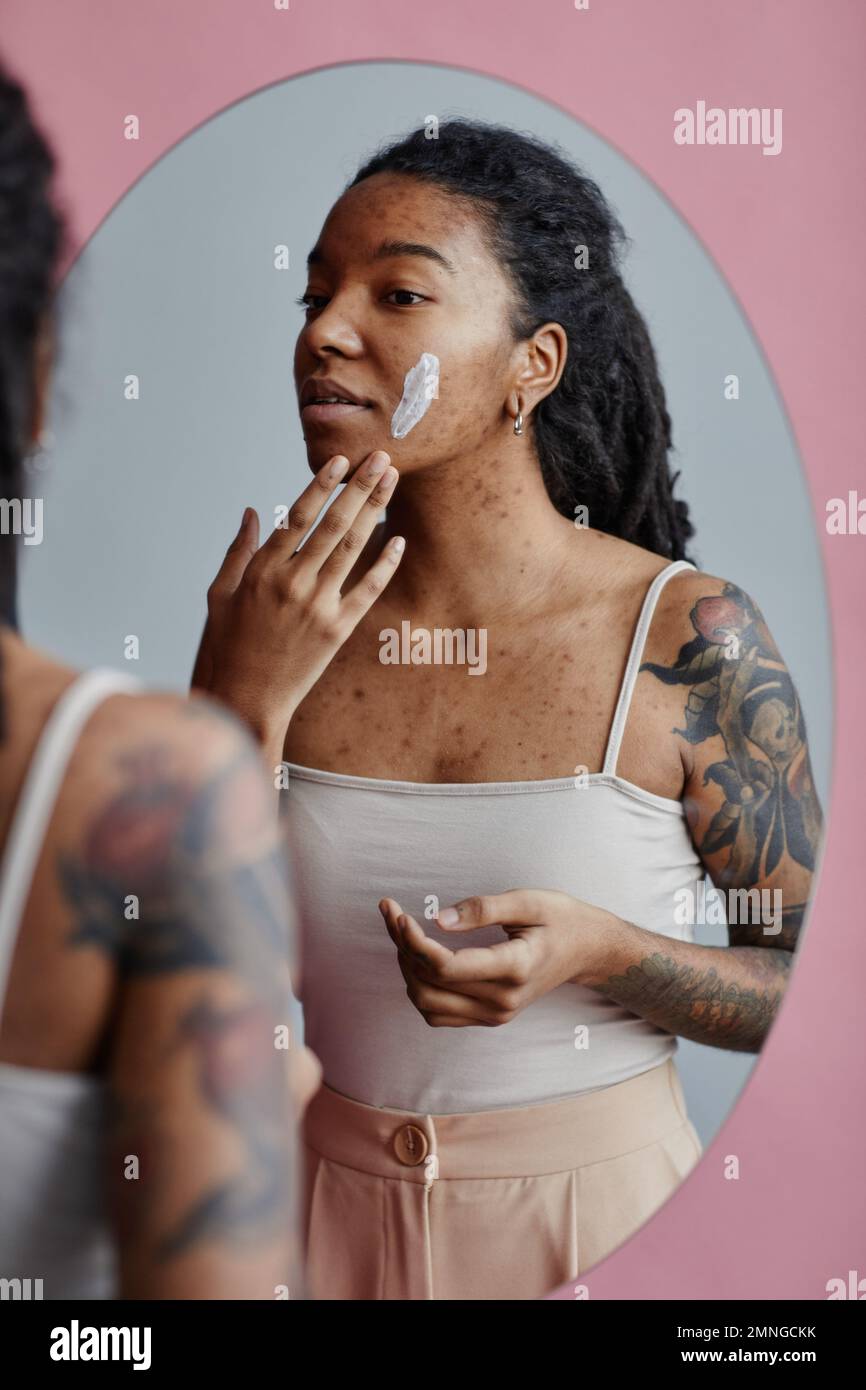 Vertical candid portrait of young black woman with acne scars using ...