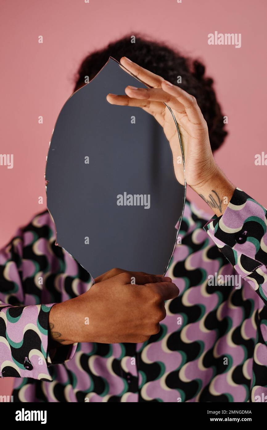 Graphic portrait of unrecognizable black woman holding mirror by face ...