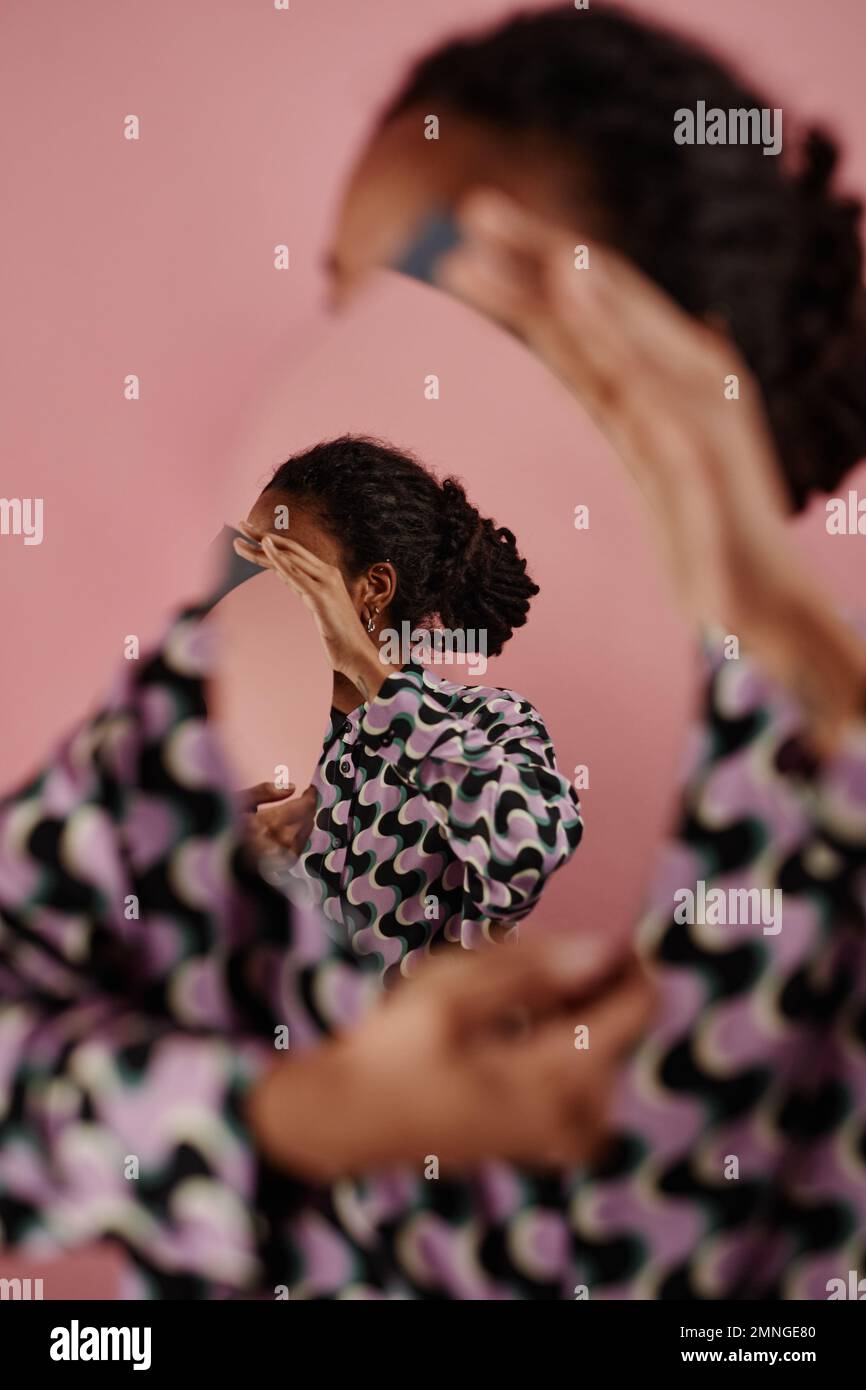 Graphic portrait of unrecognizable black woman holding mirror with ...
