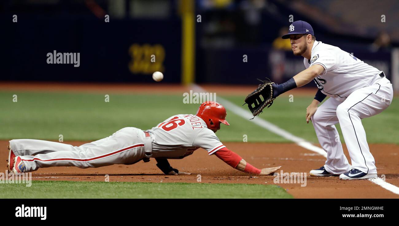 Philadelphia Phillies' Cesar Hernandez, left, dives back safely to ...