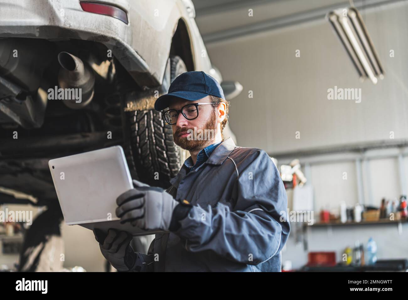 Skilled car mechanic using a computer to diagnose and fix the white car ...
