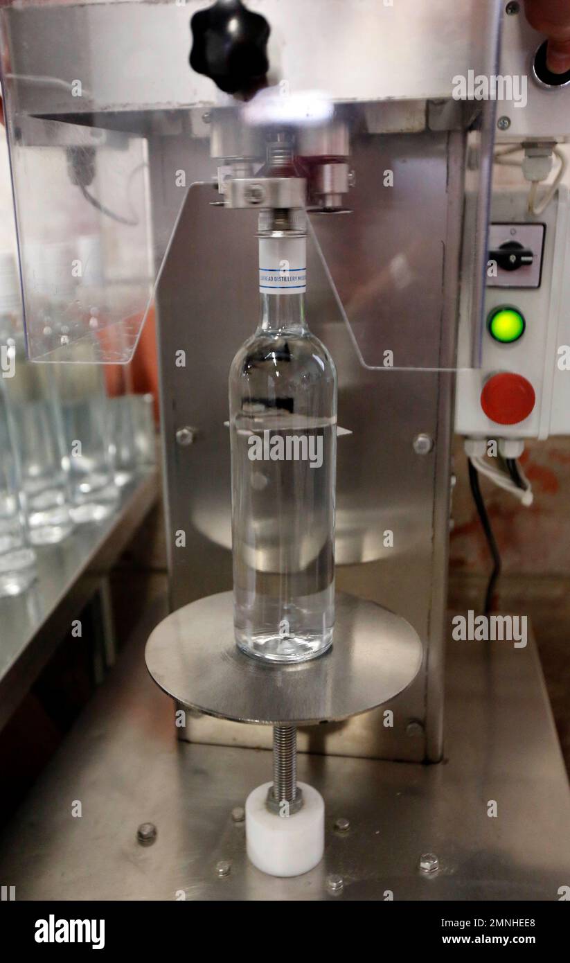 A bottle of vodka has its cap sealed before receiving a label at the ...