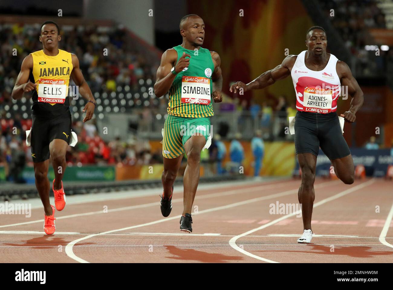 South Africa's Akani Simbine, centre, crosses the finish line in his ...