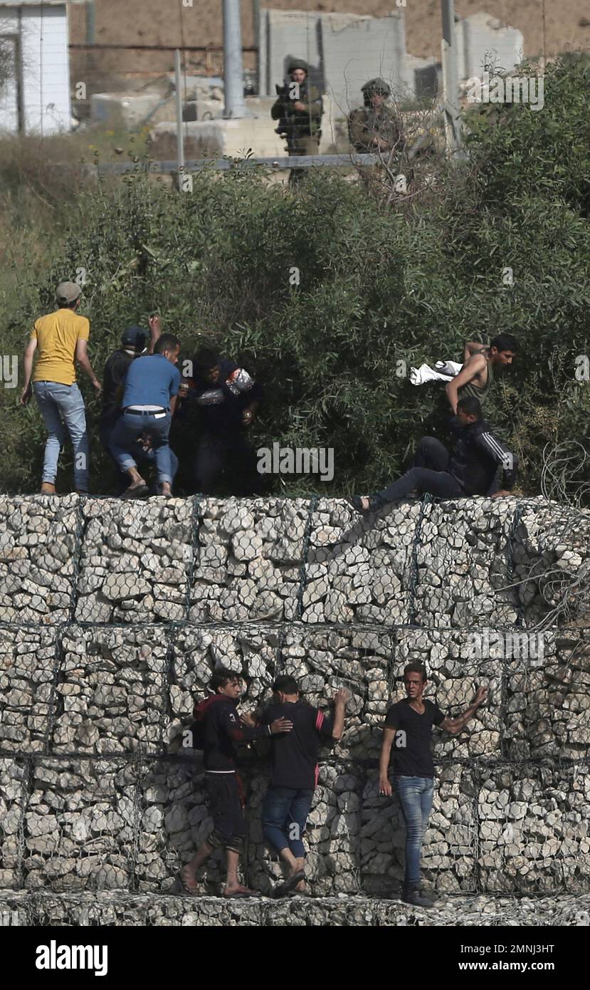 Palestinian protesters take cover from Israeli soldiers during a ...