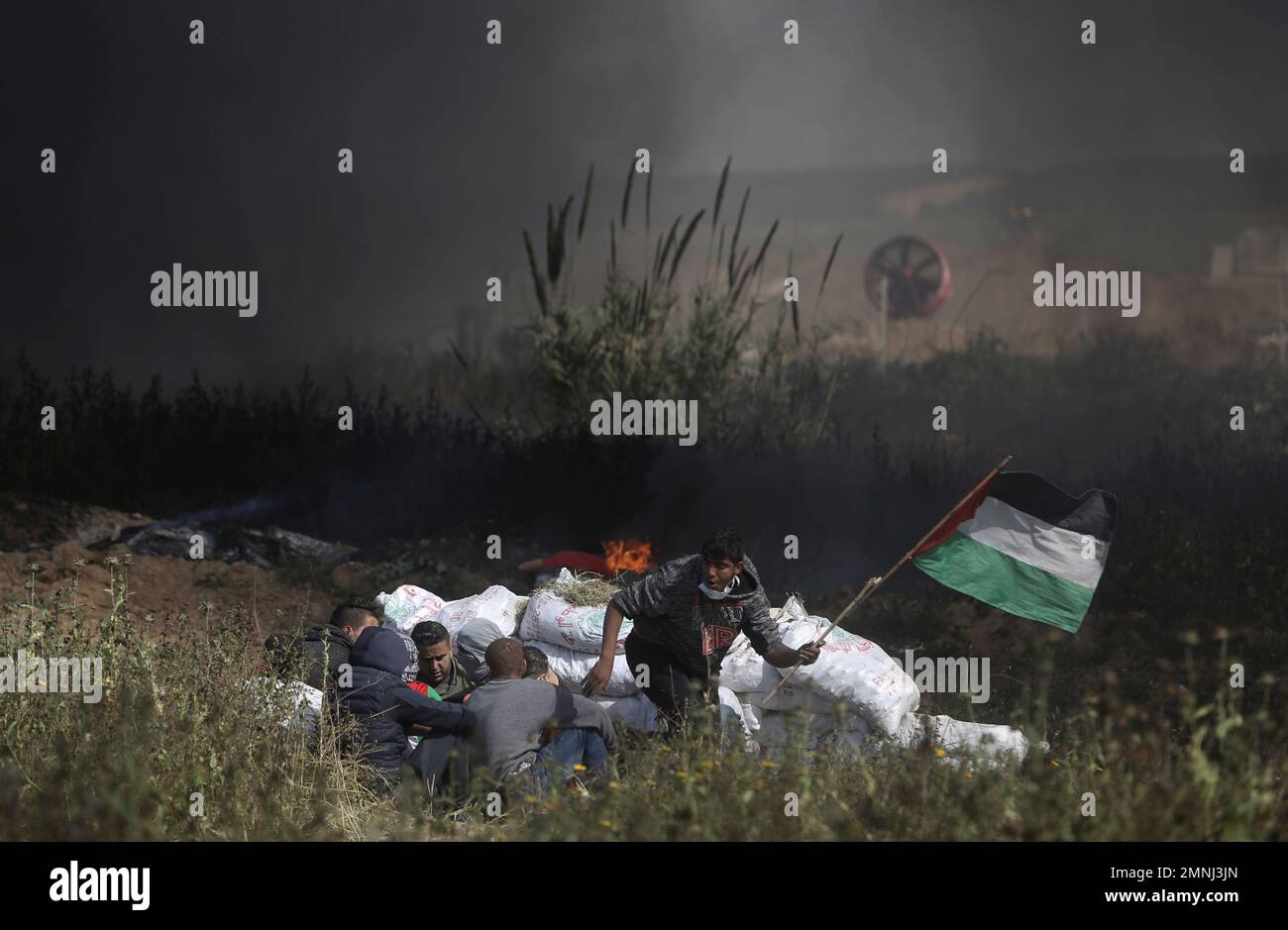 Protesters one holding a Palestinian flag take a cover during a protest ...