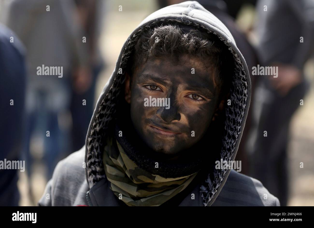 A Palestinian boy poses for a photograph as he paints his face in black ...