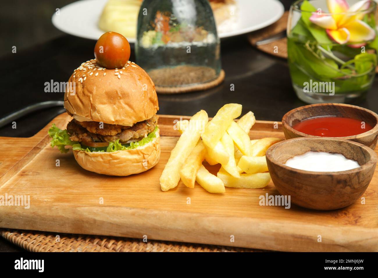Small size burger served with french fries and sauces on the wooden ...