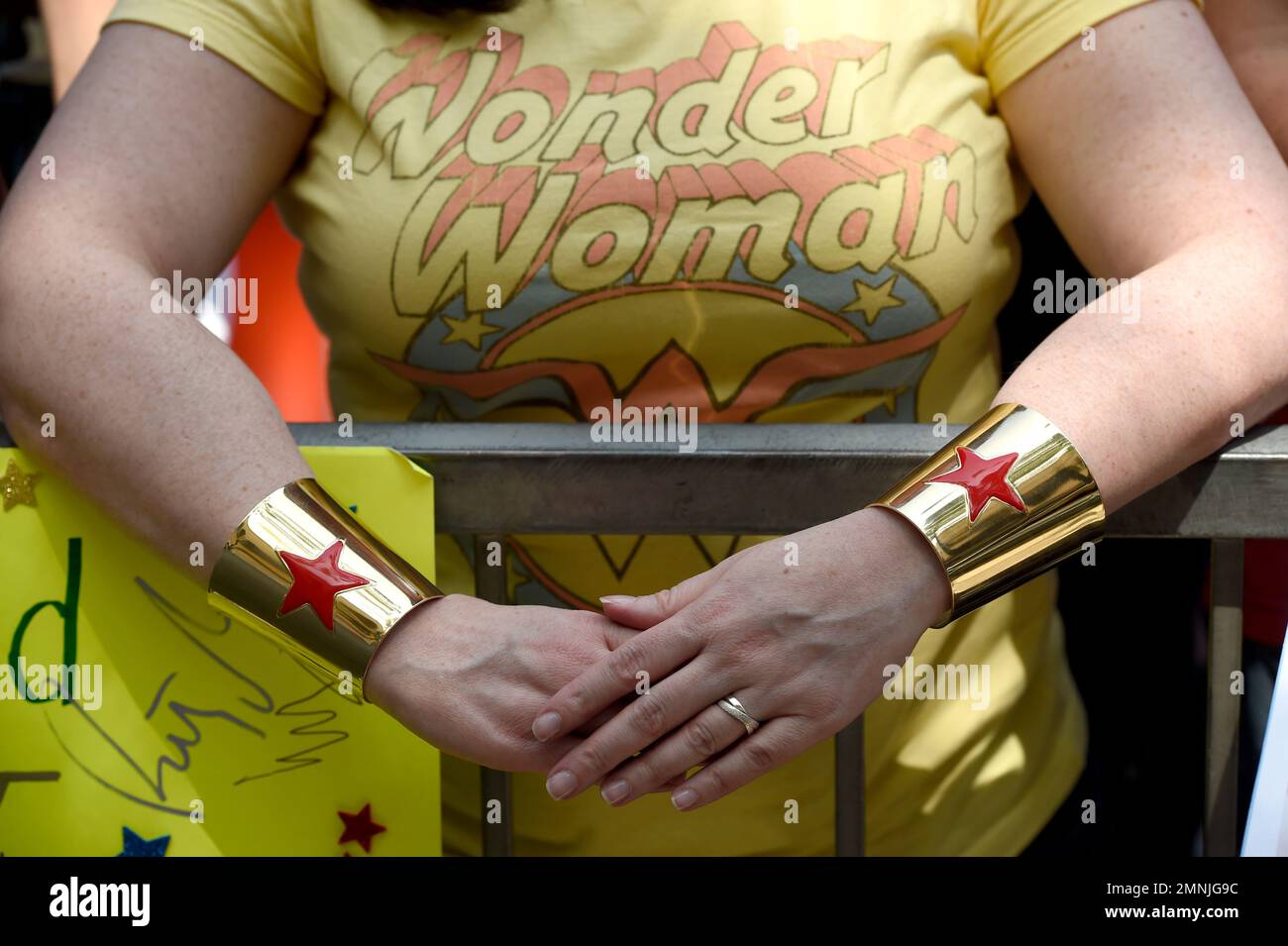 A fan wearing Wonder Woman bracelets and shirt attends a ceremony ...