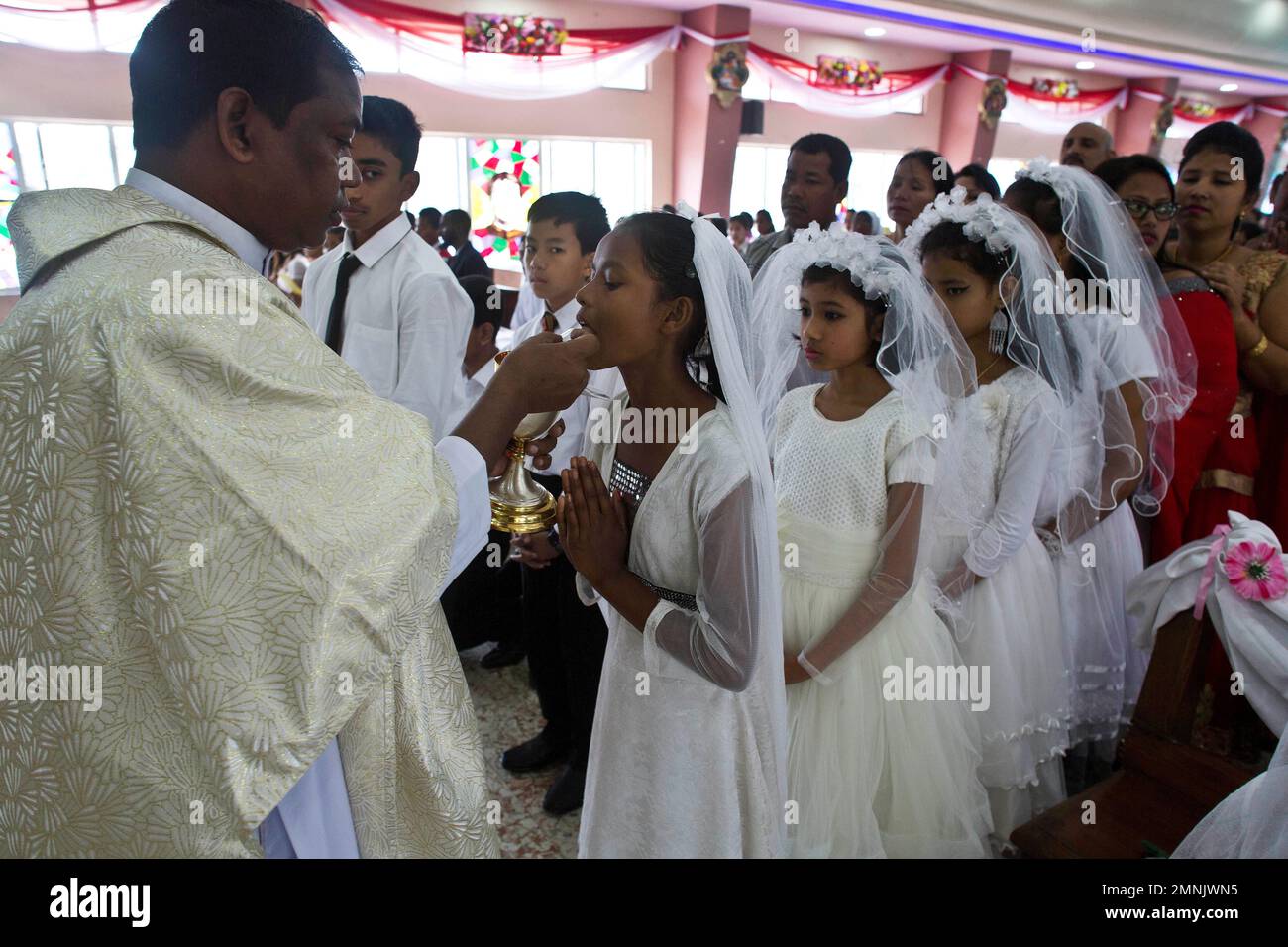 An Indian Catholic priest offers holy communion to Christian girls ...