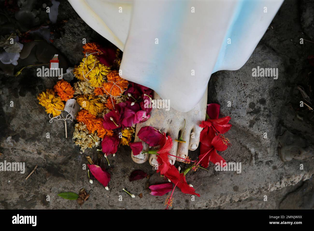 An offering of flowers is placed at the foot of a statue of Jesus ...